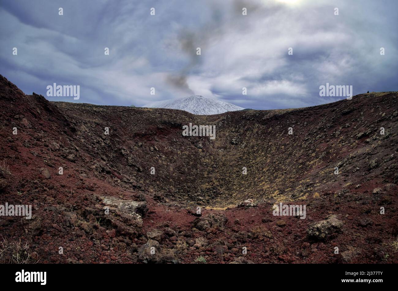Roche volcanique rouge de l'ancien cratère et fumée sombre de l'Etna ...