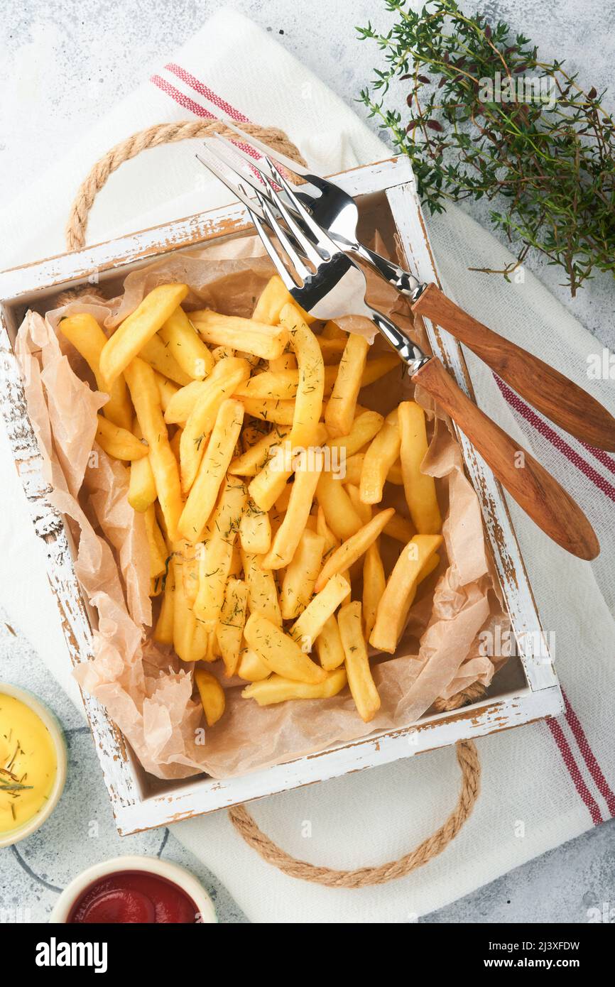 Frites. Assiette de frites savoureuses sur papier parchemin sur planche ...