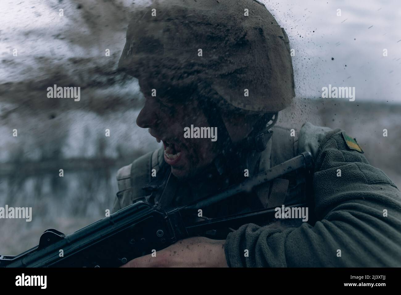 Un soldat ukrainien se tient avec le fusil d'assaut kalachnikov pendant ...