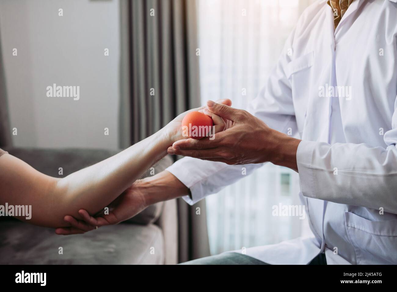 Un jeune physiothérapeute asiatique aide le patient à lever des ...