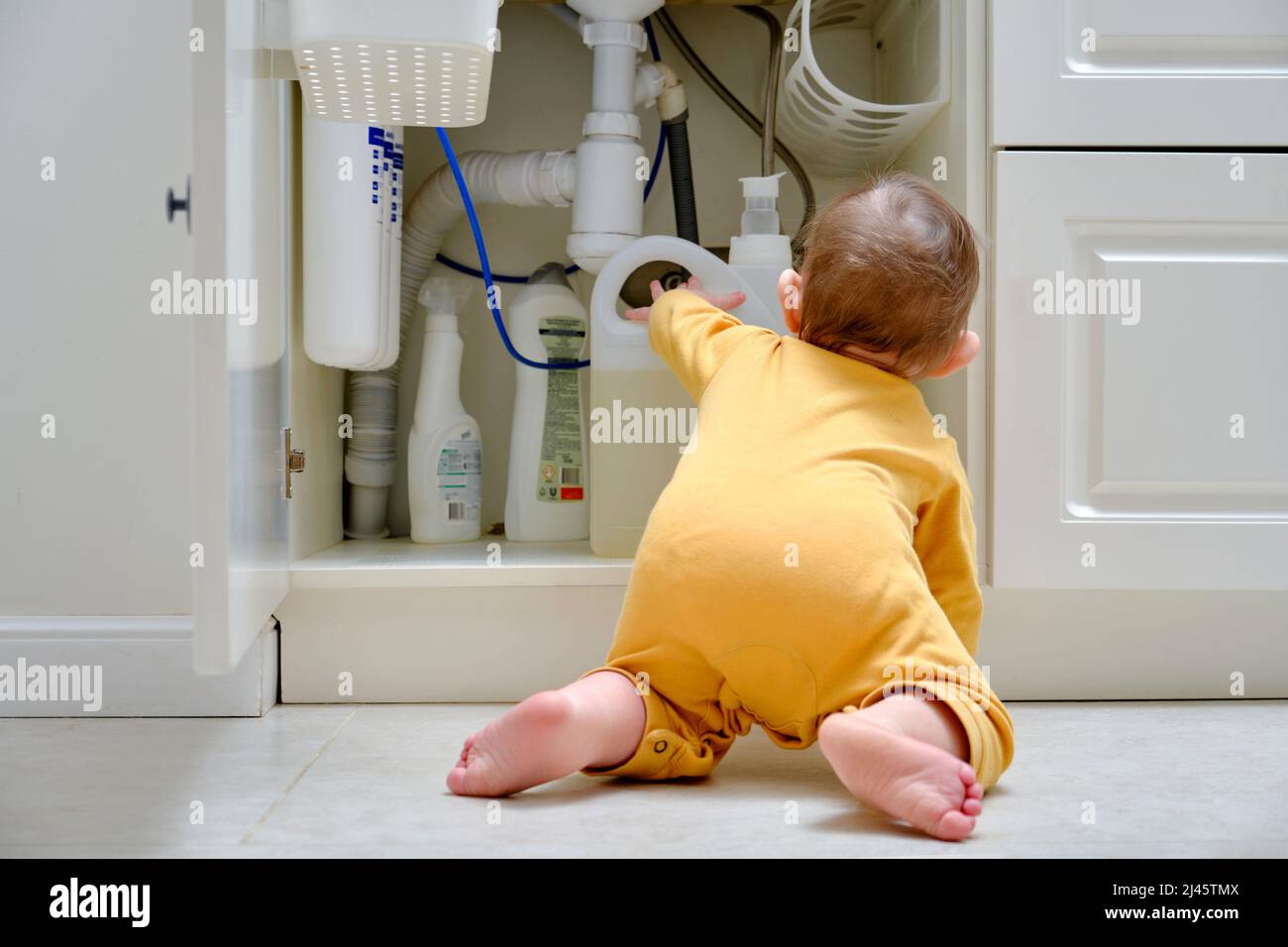 Bébé garçon joue avec des détergents et des produits de nettoyage dans ...