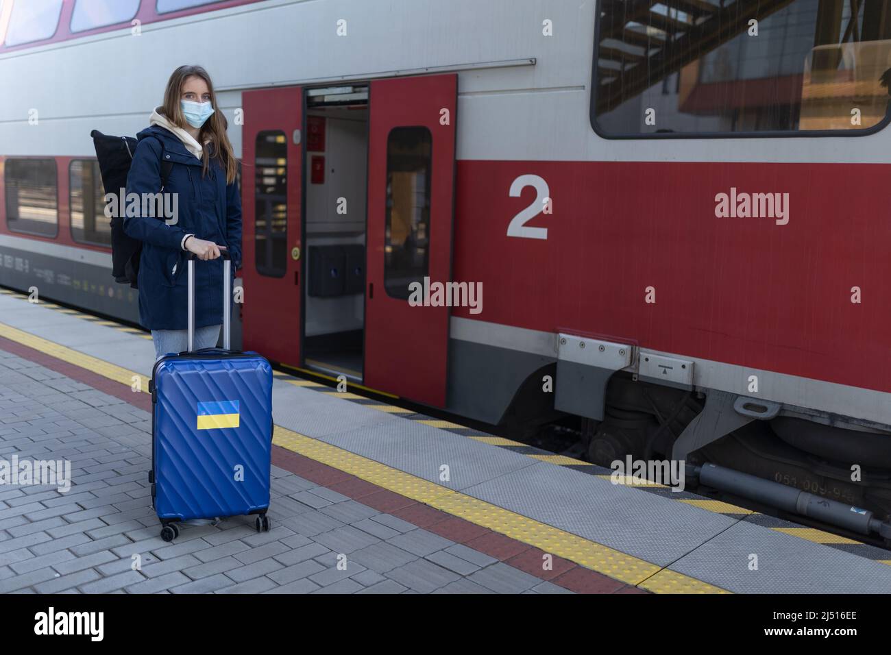 Une jeune femme ukrainienne avec une valise attendant le train à la ... Une jeune femme ukrainienne avec une valise attendant le train à la ...