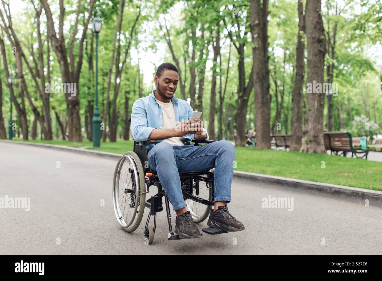 Pleine longueur de jeune homme noir en fauteuil roulant utilisant le ...