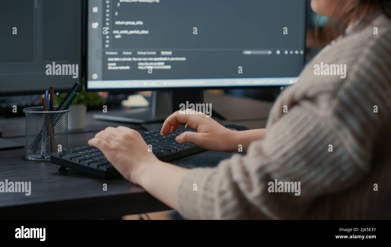 Gros plan du codeur de logiciel caucasien mains dactylographiant sur le clavier devant les ...