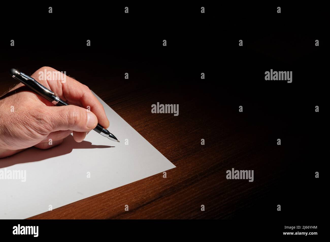 La main écrit sur du papier blanc avec un stylo. Signature manuelle d ...