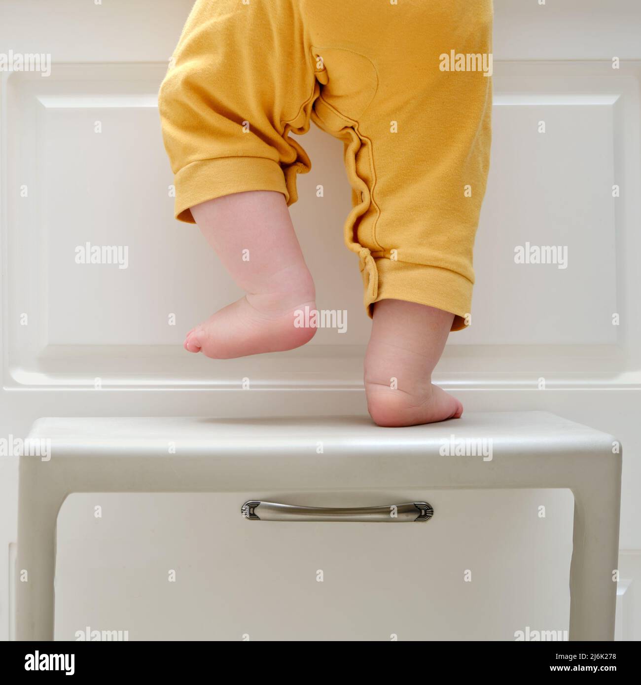 Le bébé garçon a grimpé avec ses pieds sur une chaise haute pour ...