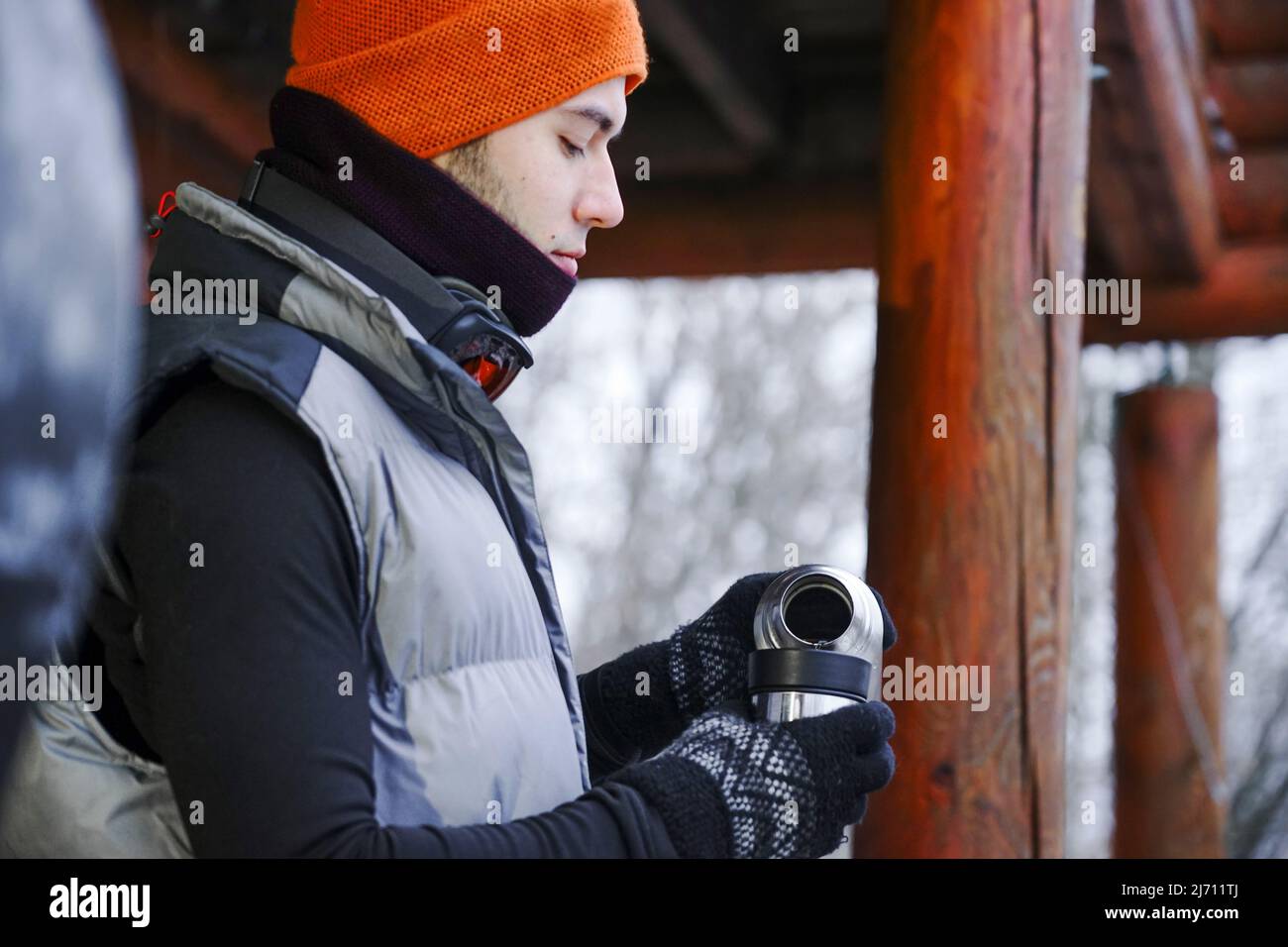 Le gars se trouve sur le balcon d'une maison en bois dans des vêtements ...