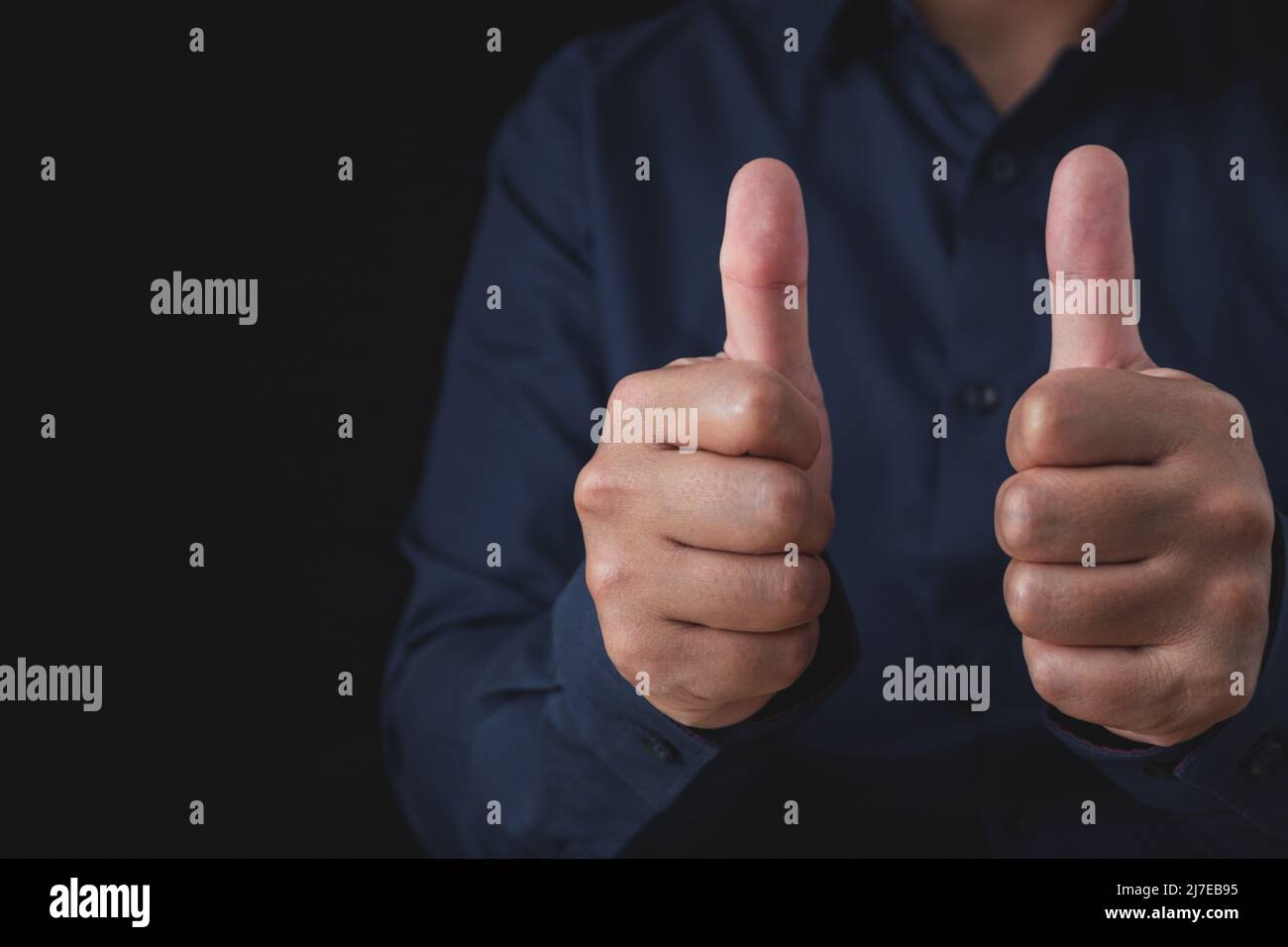 La personne qui porte une chemise bleu foncé affiche un signe de pouce ...