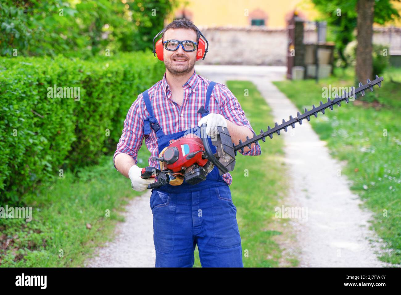 Un homme travaillant dans le jardin et le buisson à l'aide d'un taille ...