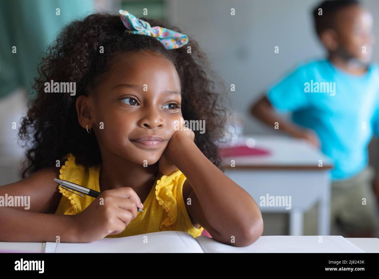 Gros plan sur une écolière afro-américaine bien réfléchie, assise à un ... Gros plan sur une écolière afro-américaine bien réfléchie, assise à un ...
