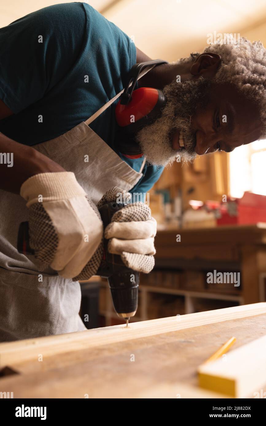 Souriant menuisier afro-américain mature faire le trou avec le foret ...