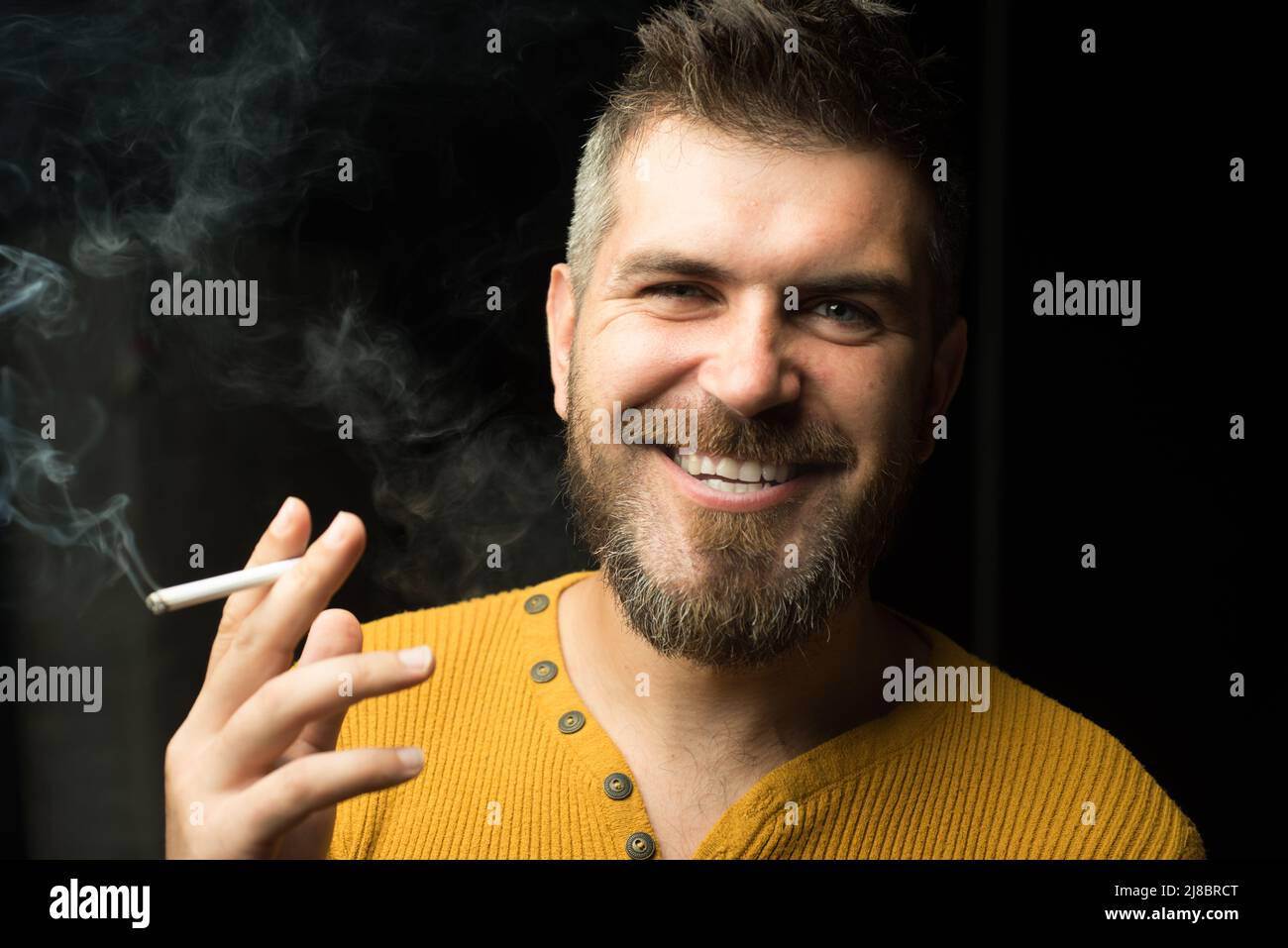 Homme souriant fumant. Fumée sur fond noir. Dépendance au tabagisme ...