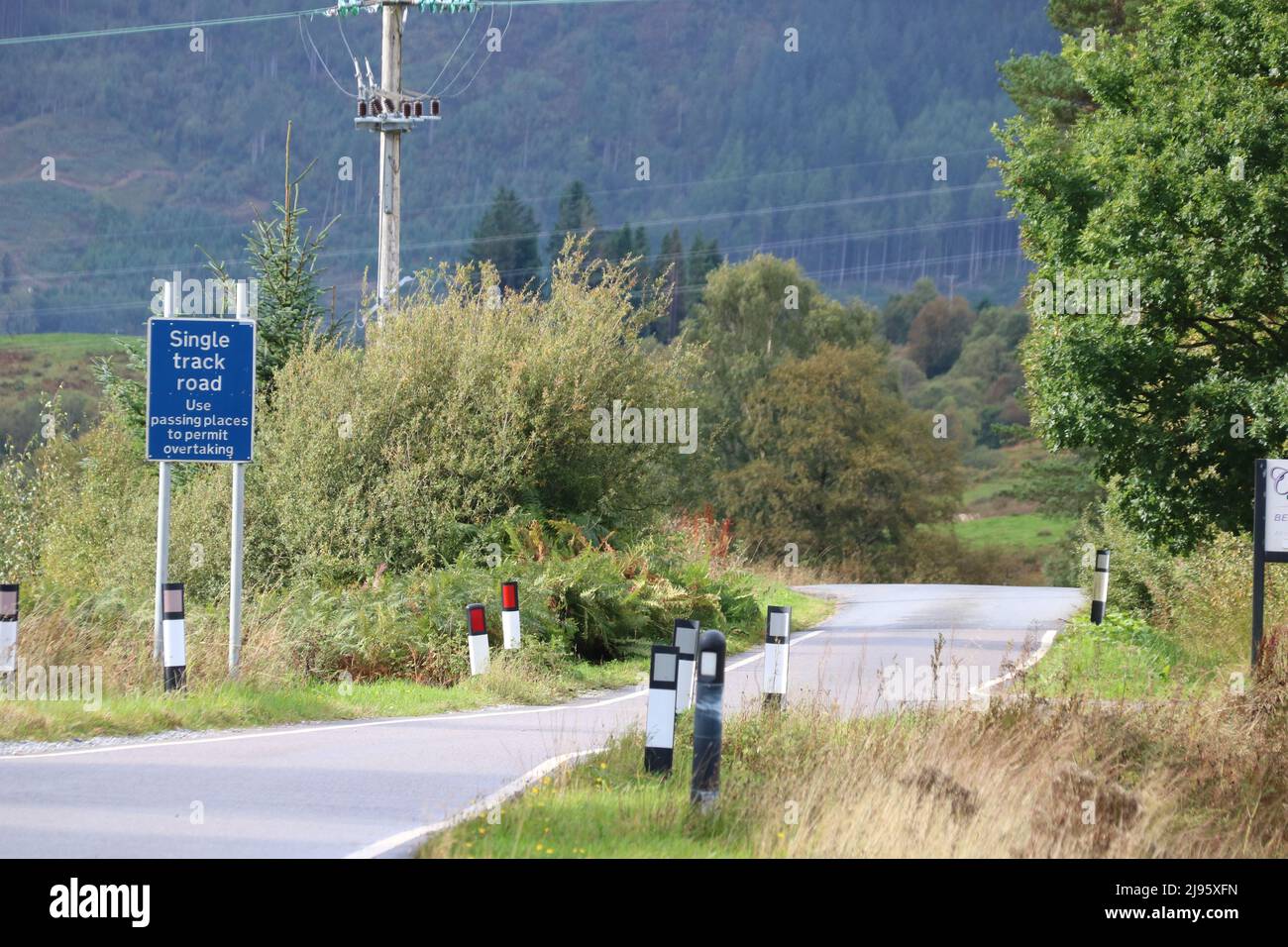 Une route étroite descendant une colline avec un panneau d ...