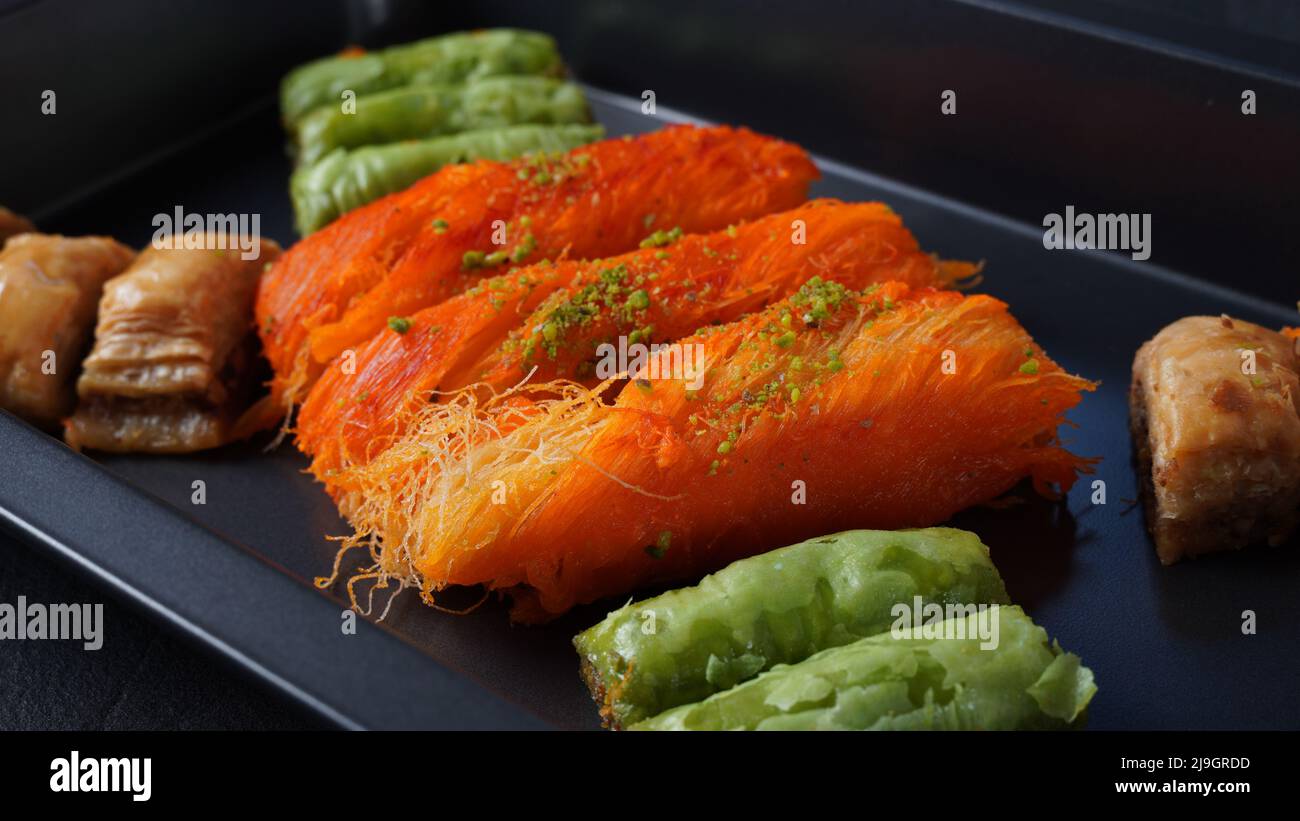 Un plateau de pâtisseries turques comprenant du baklava, du knafeh ...