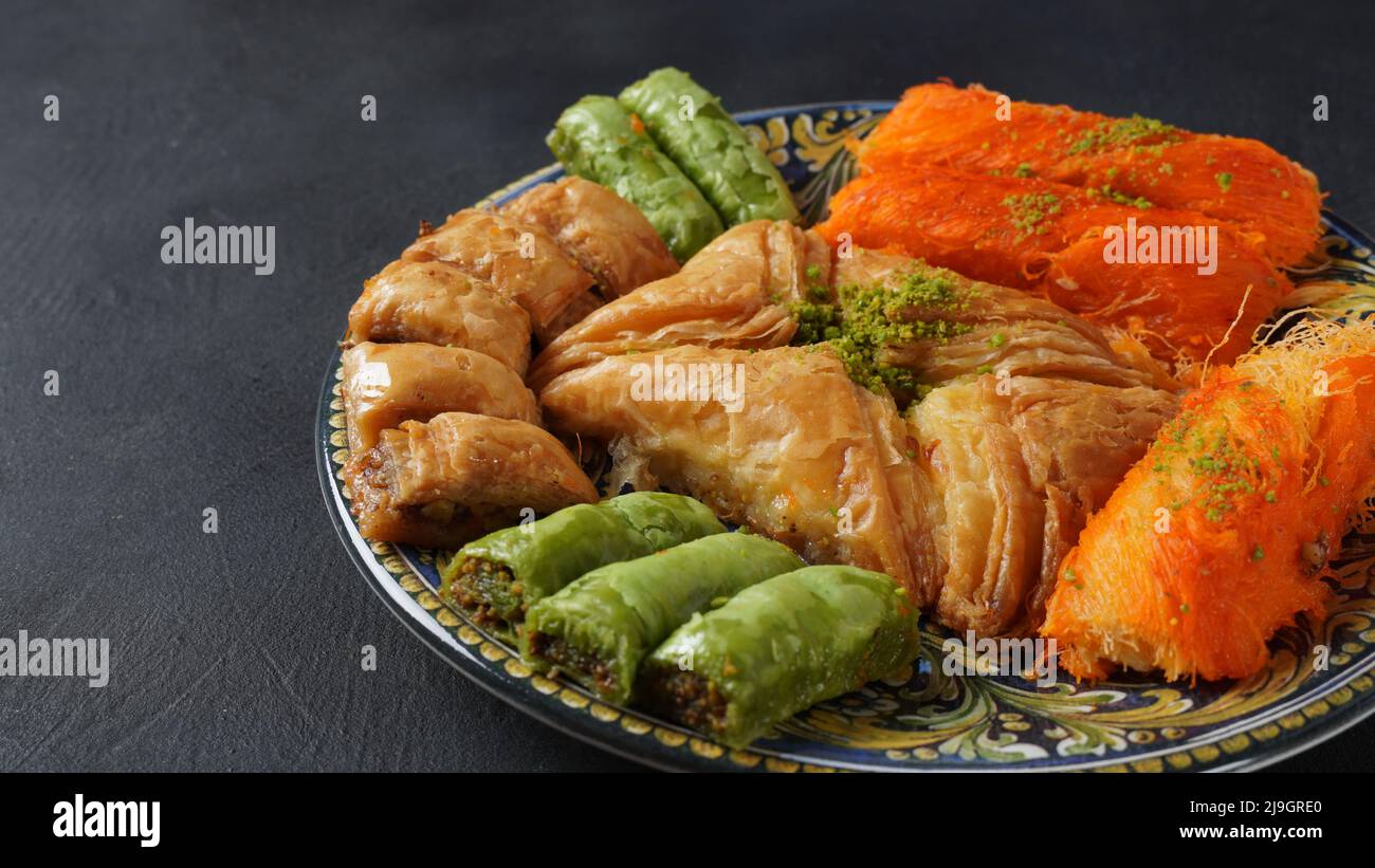 Un plateau de pâtisseries turques comprenant du baklava, du knafeh ...