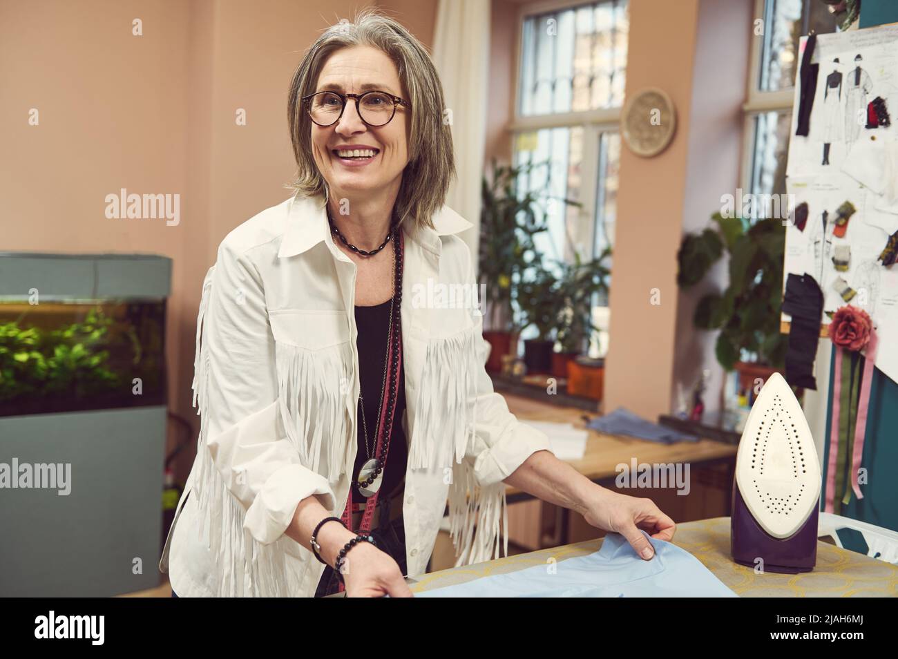 Femme européenne mûre et élégante, couturière, sur mesure en souriant ...