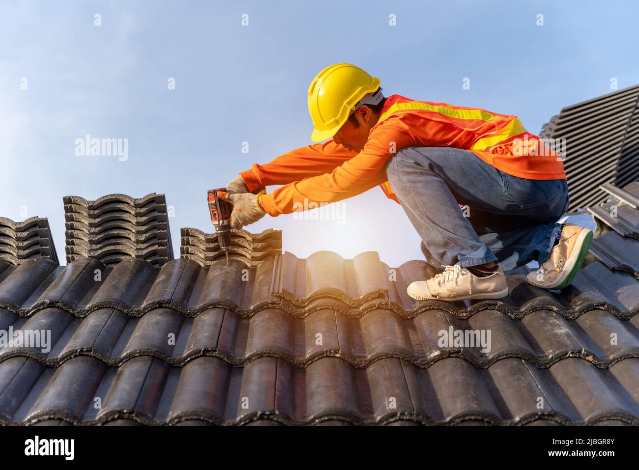 Le Roofer asiatique travaille sur la structure de toit du bâtiment sur ...