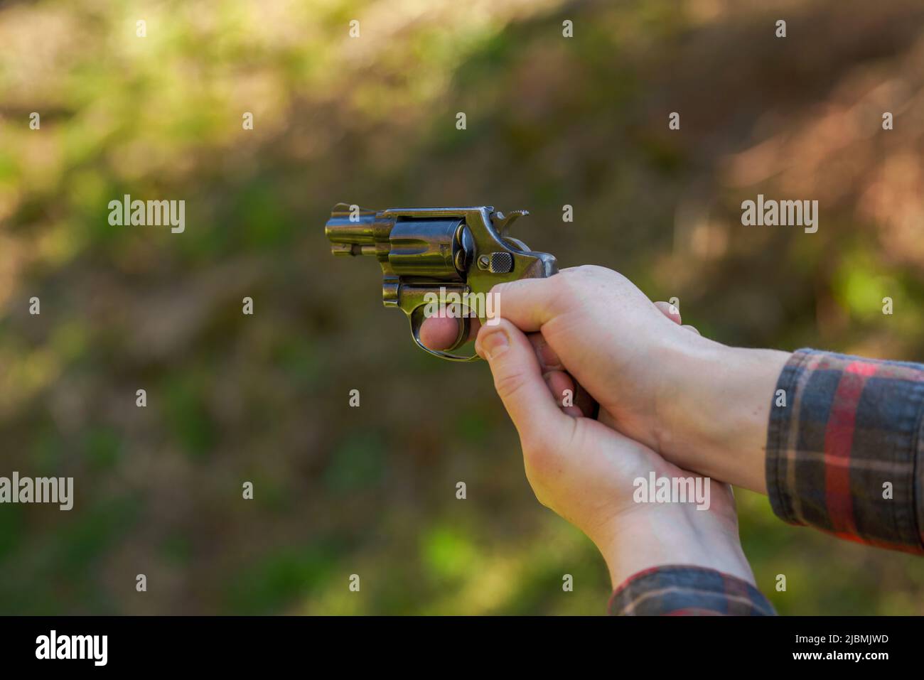 Homme méconnaissable avec revolver visant la cible sur la portée de tir ...
