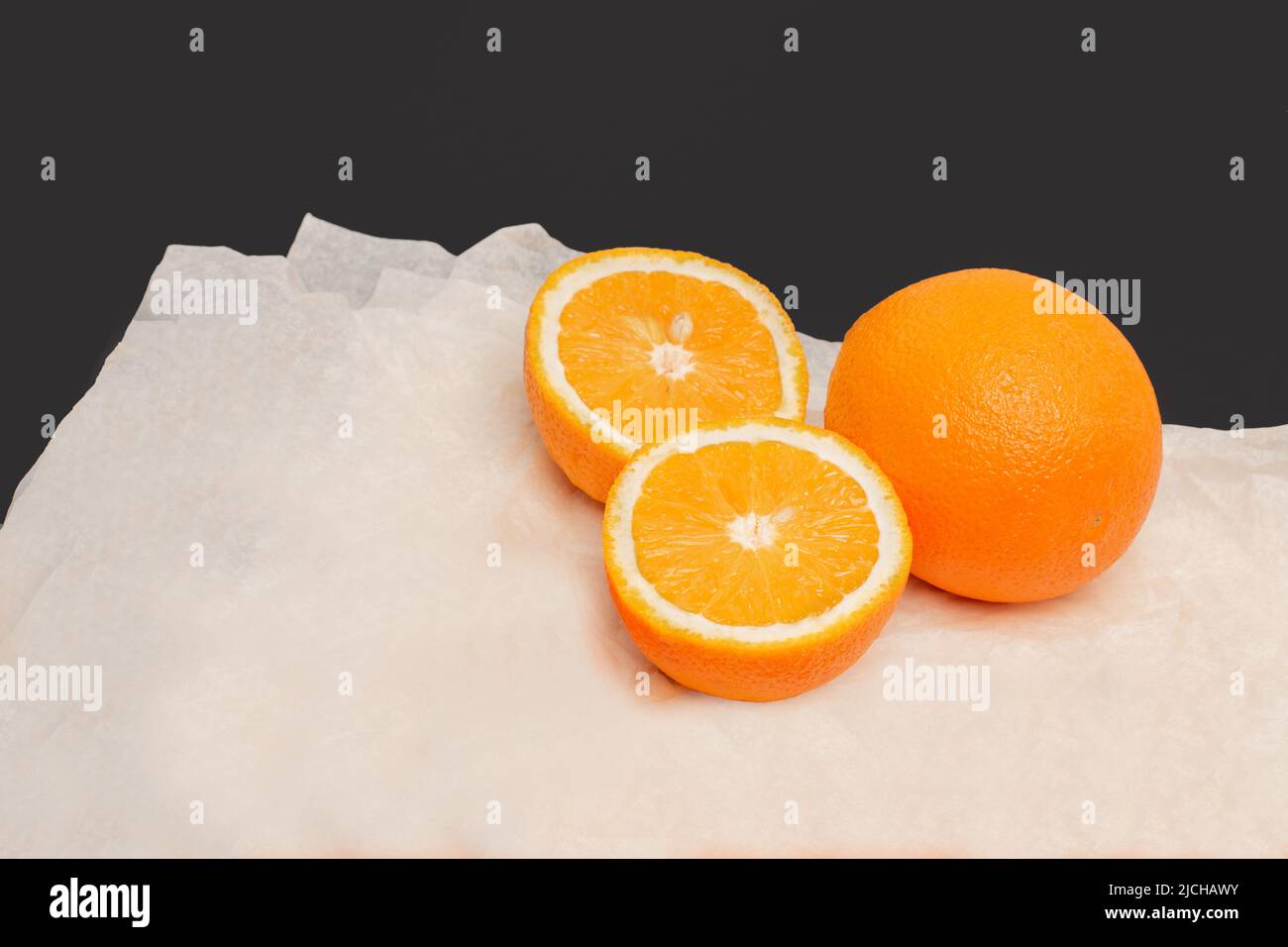 Deux oranges, dont l'une a été coupée. Les fruits se trouvent sur du ...