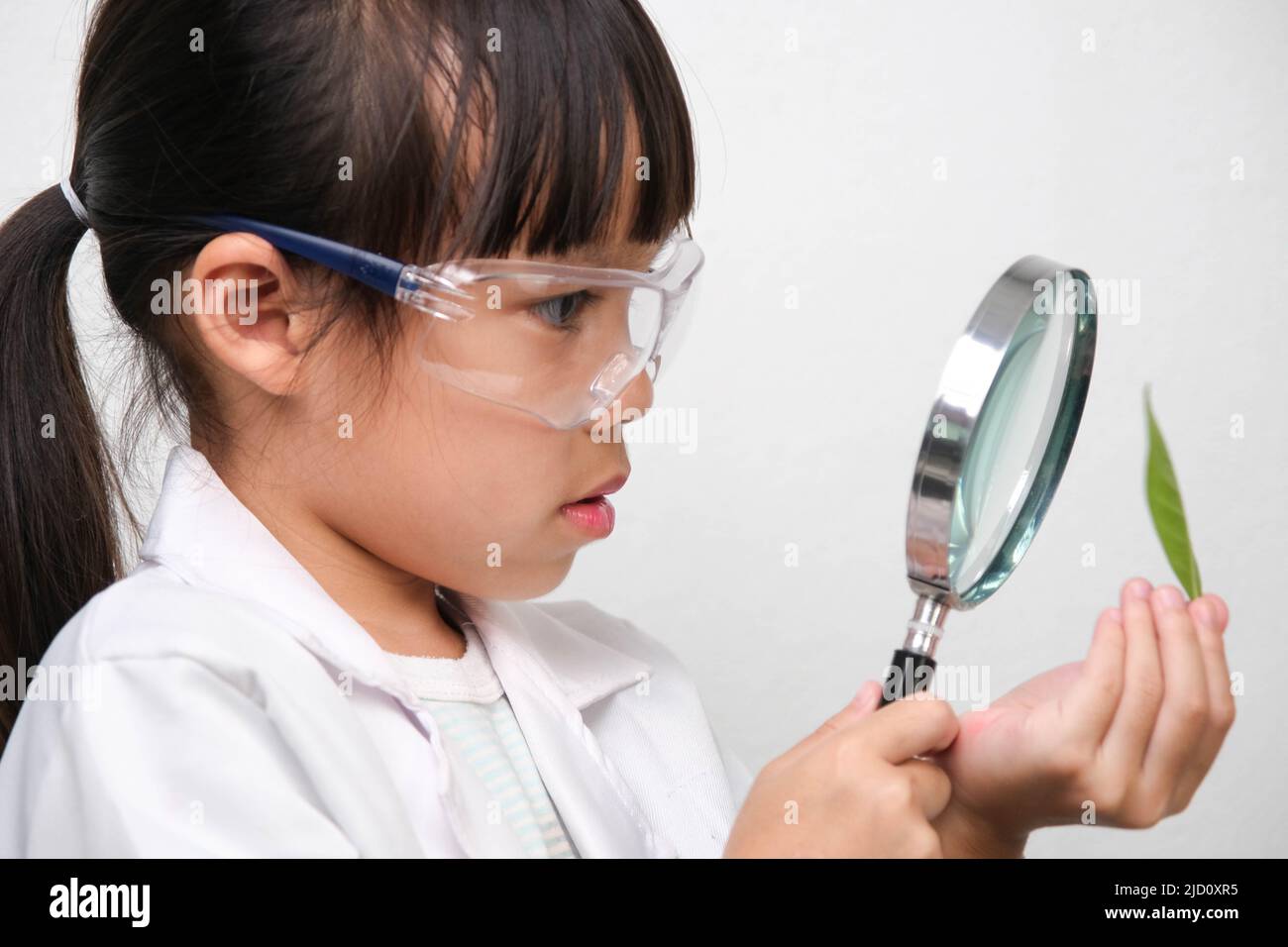Portrait d'une petite fille dans des lunettes tenant une loupe ...