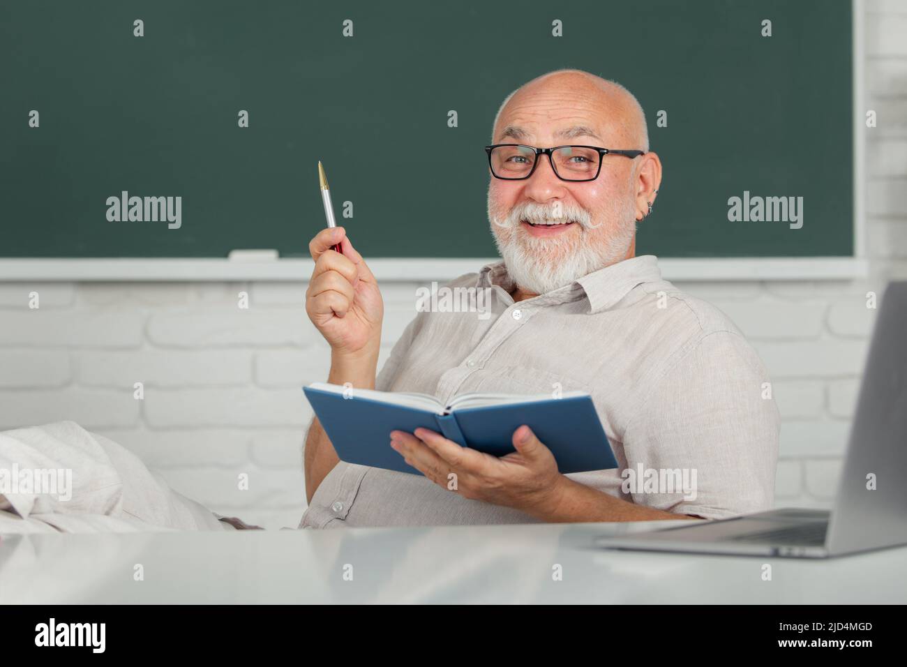 Professeur senior souriant enseignant dans la salle de classe sur ...