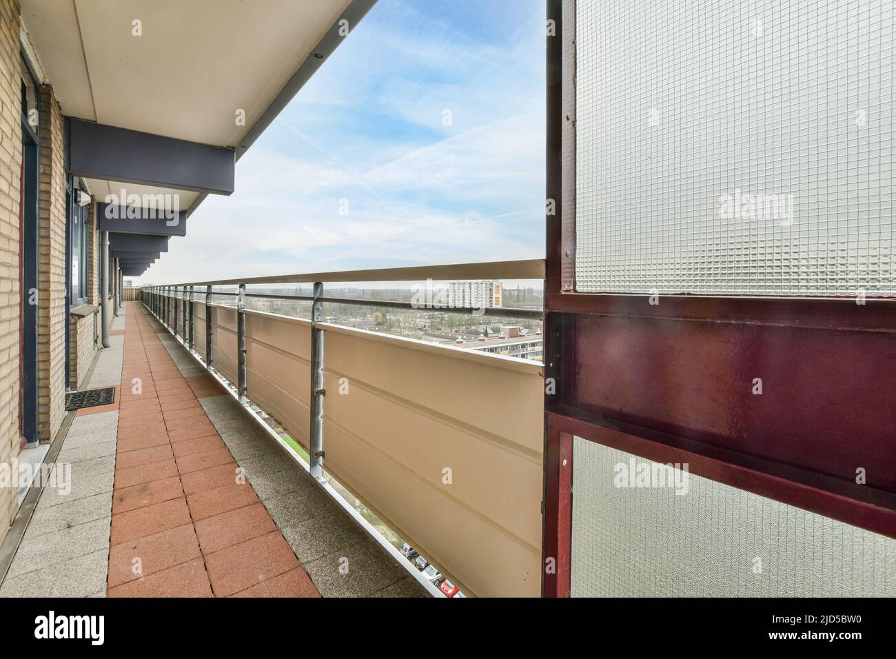 Balcon étroit en briques avec rambardes en métal, chaise en bois et ...