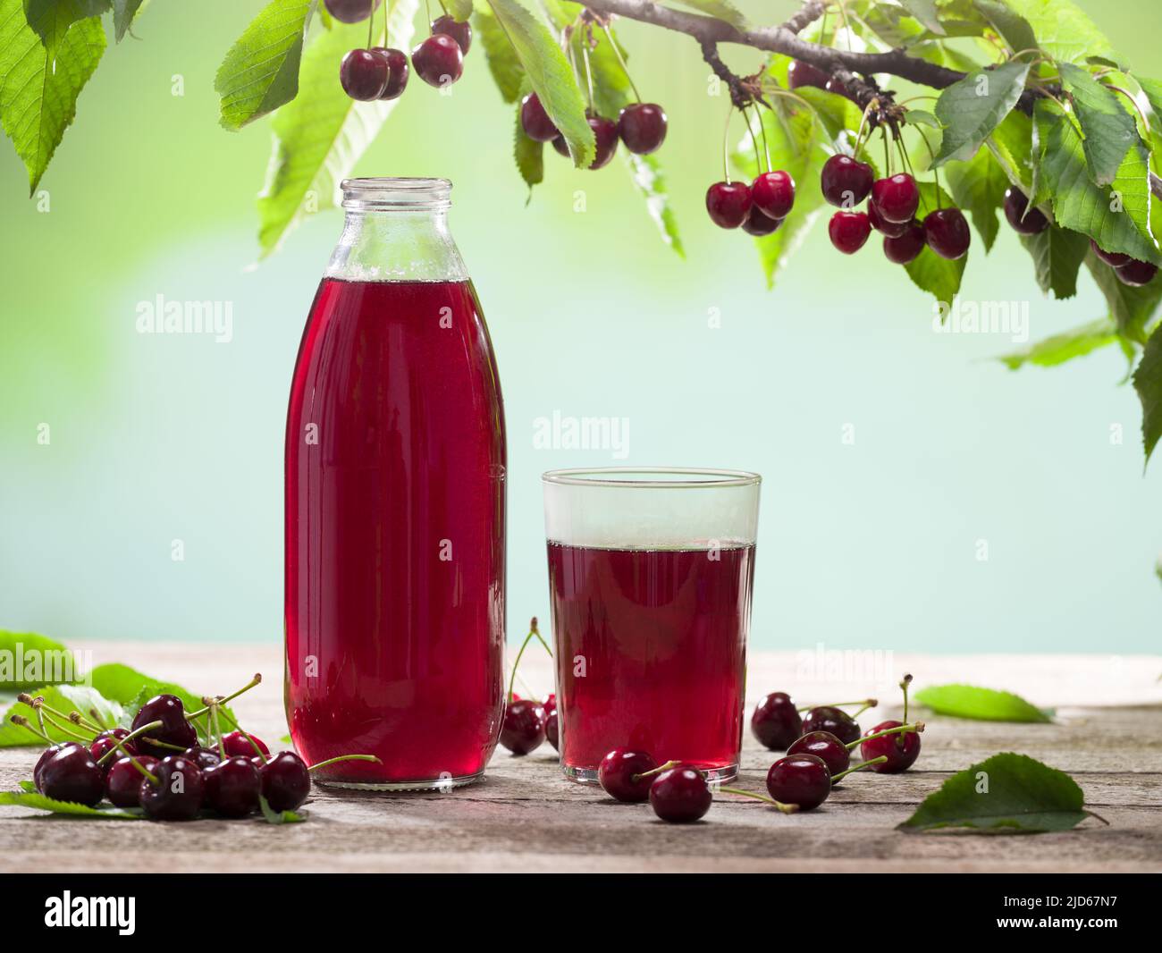Jus de cerise frais sur la table du jardin. Un verre de jus de cerise ...