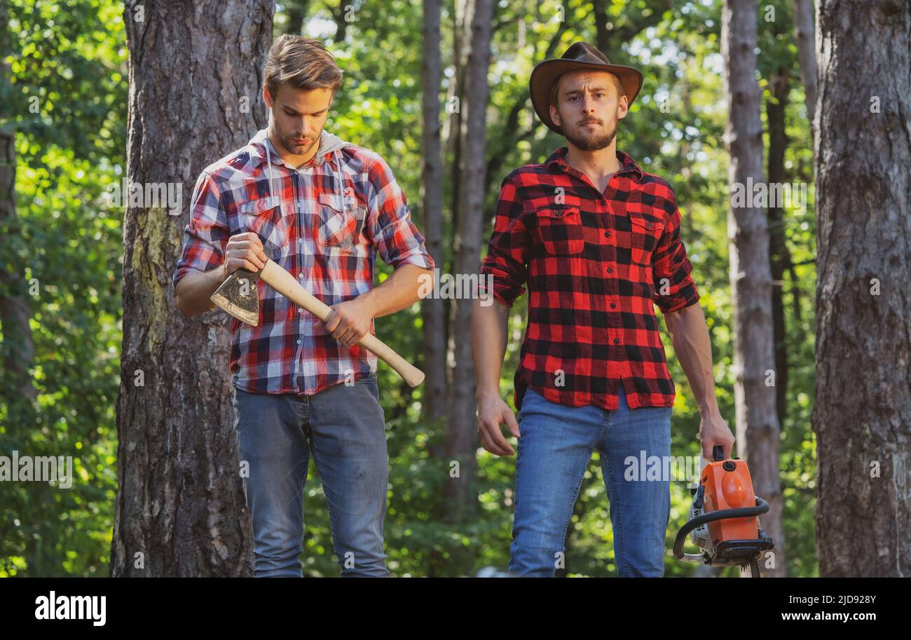 Deux bûcherons avec tronçonneuse et hache.Bûcheron mâle dans la forêt ...