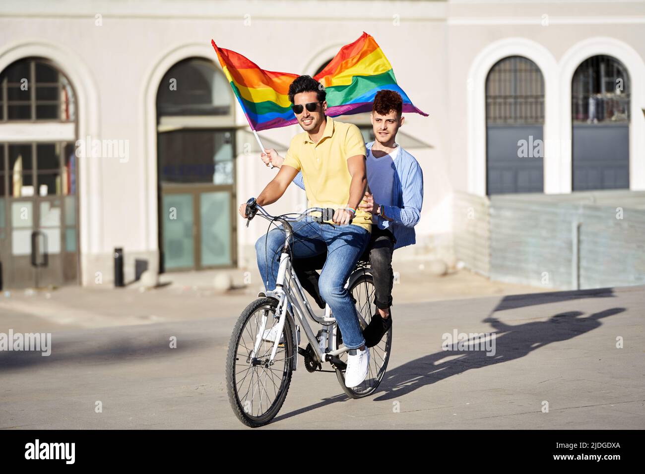 Jeune couple gay tenant un drapeau de fierté gay tout en faisant un ...