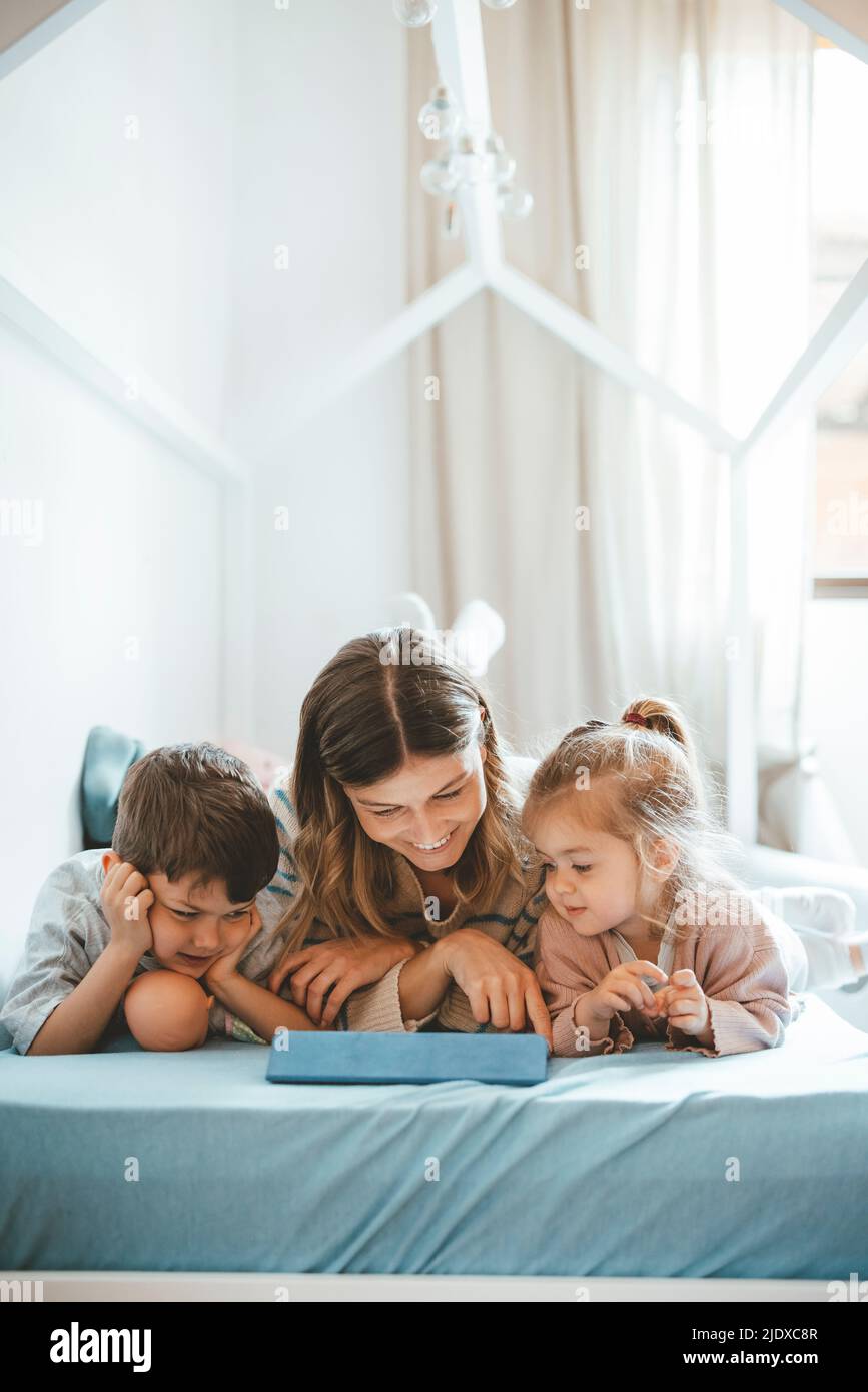 Femme Souriante Avec Son Fils Et Sa Fille Regardant Un Pc Tablette