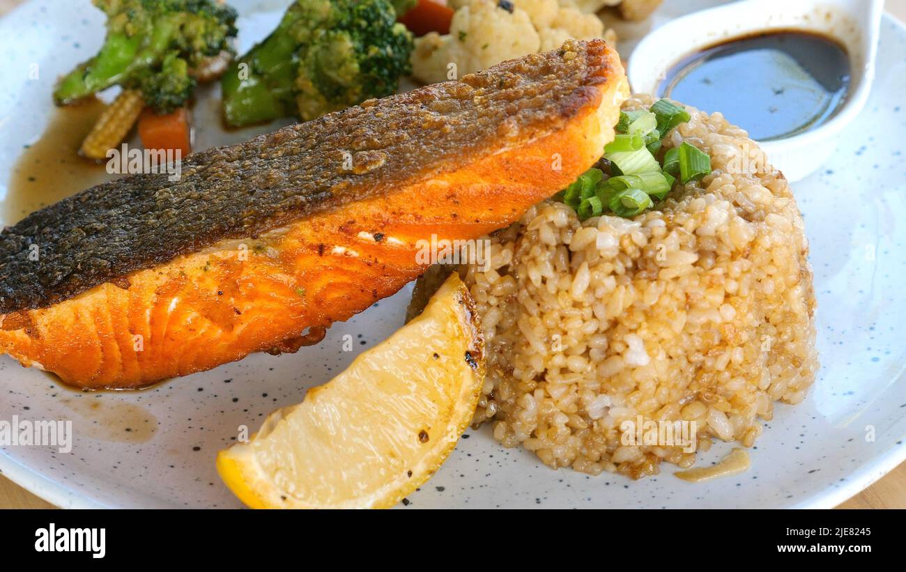 Filet de saumon grillé avec riz à l'ail, épices et légumes frits. Des ...