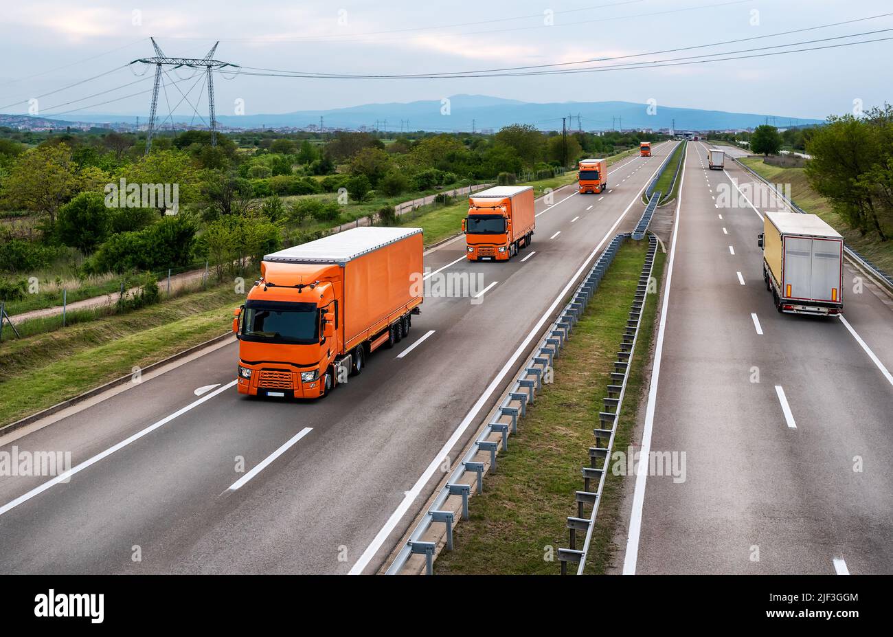 Transport sur route à quatre voies avec des camions de transport orange ...