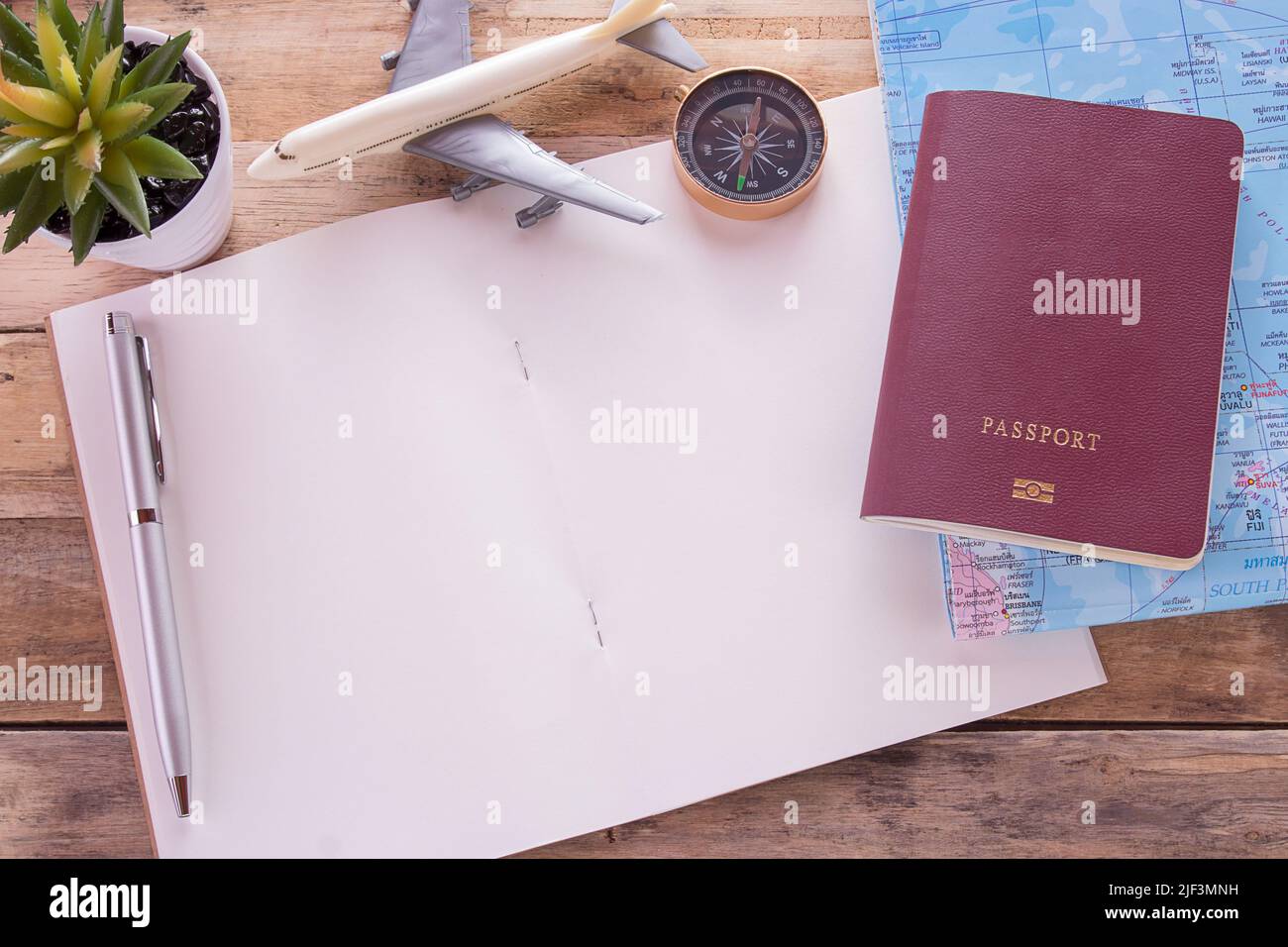 Carnet vierge, passeport, stylo, boussole, avion et carte sur table en ...