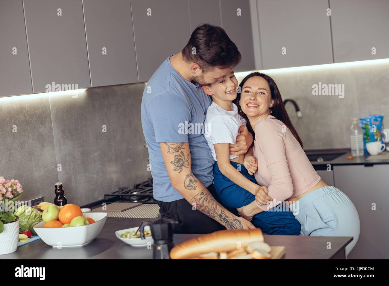 Famille caucasienne avec un petit enfant qui s'embrasse dans la cuisine le matin. Maman et papa ...