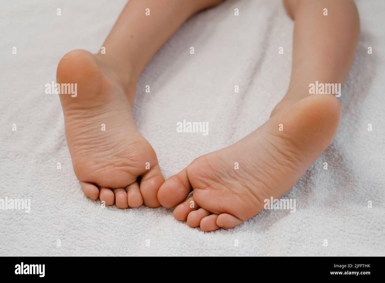Les pieds des enfants sur une serviette blanche après un massage sur le ...