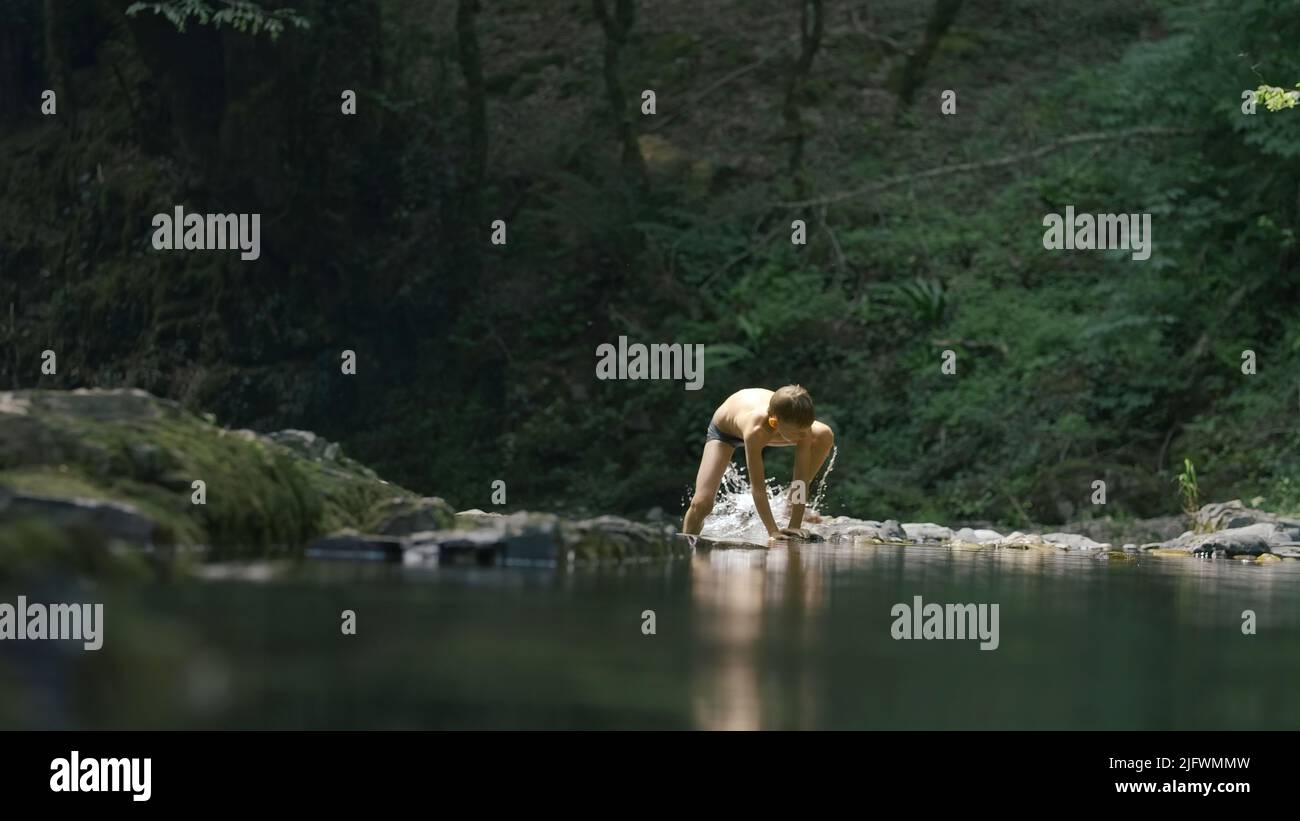 Le garçon nage dans un étang naturel froid. Créatif. Un garçon plonge ...
