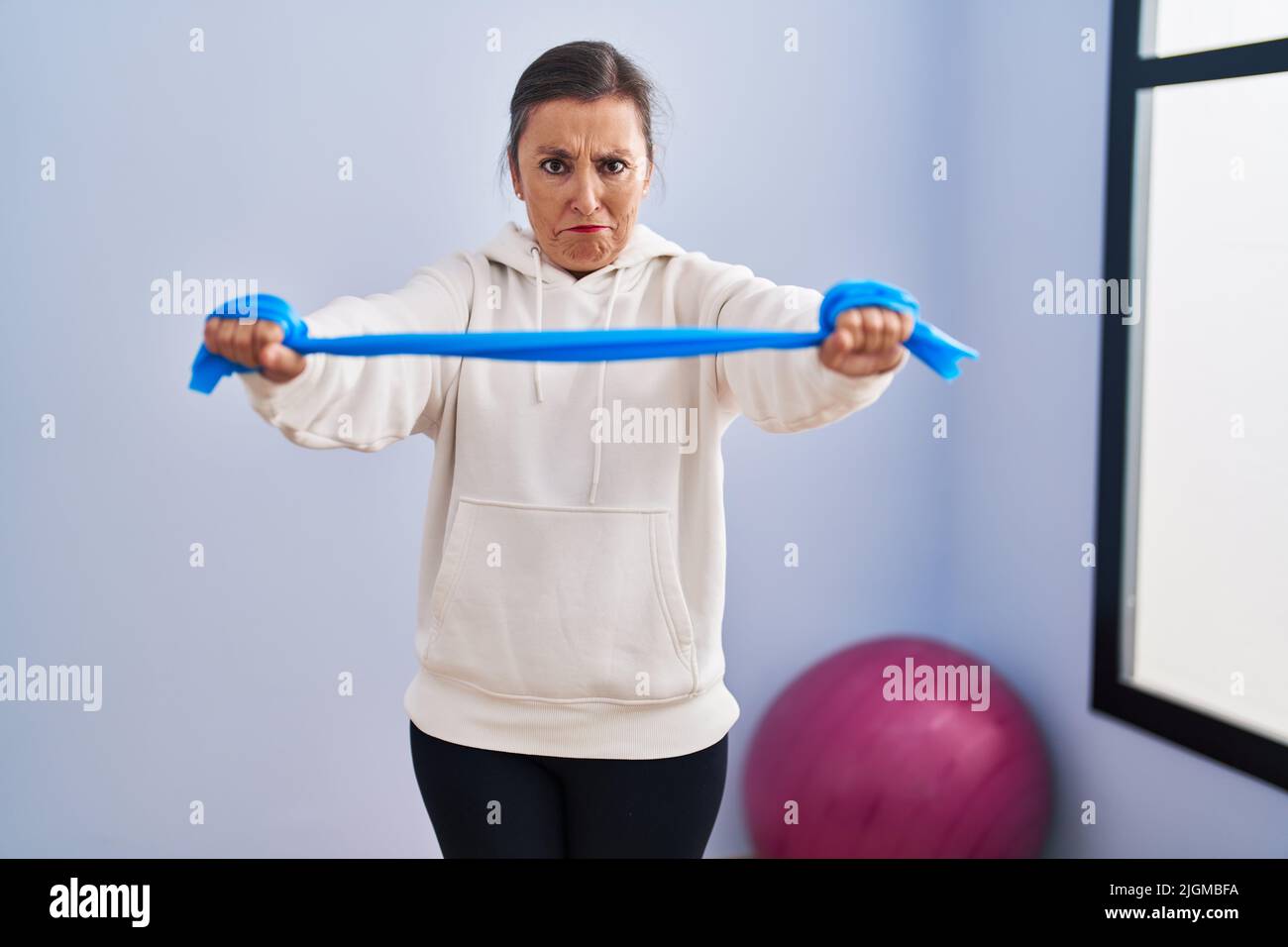 Femme hispanique d'âge moyen entrainement de la résistance de bras avec ...