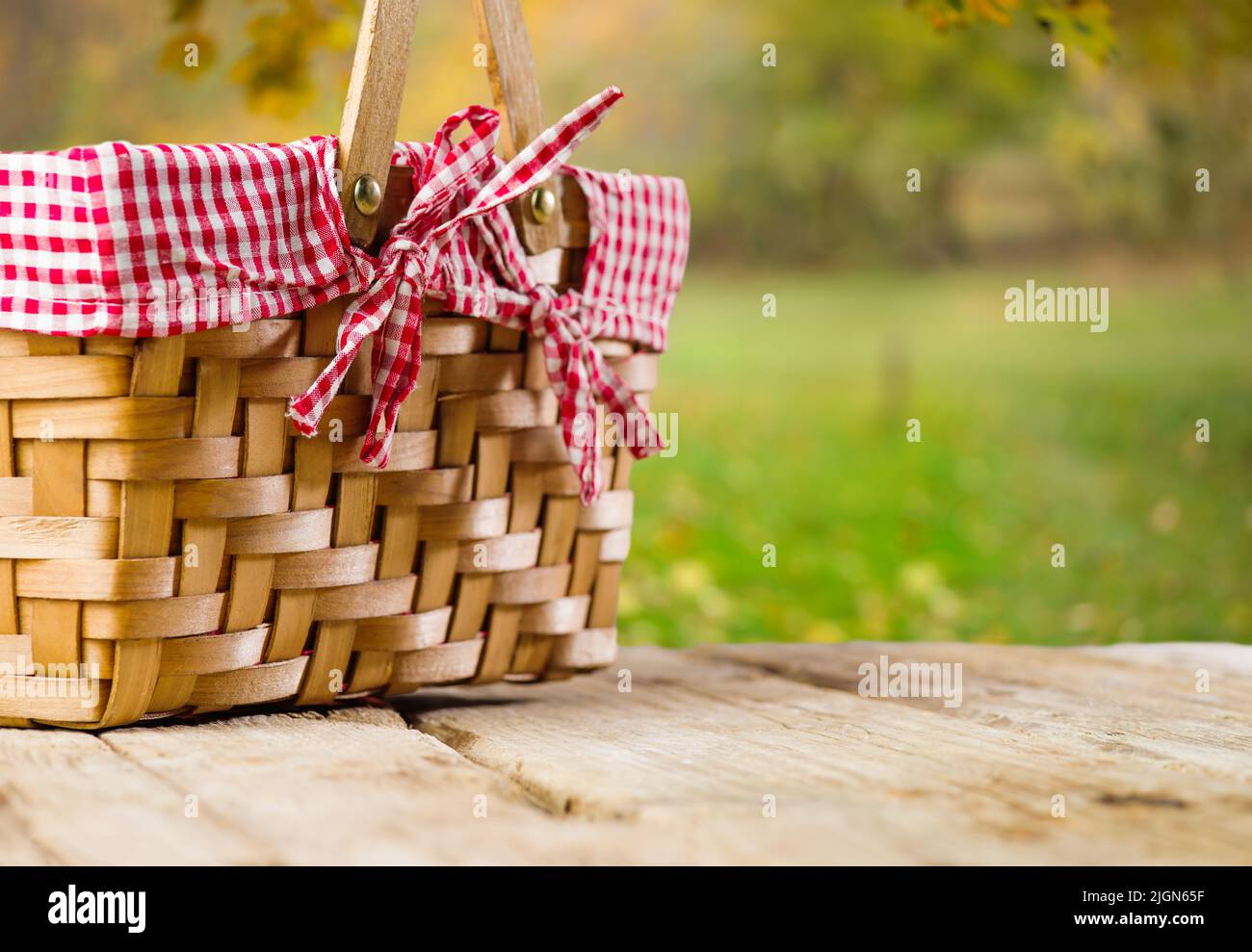 Sur une table en bois, un panier pique-nique en paille sur fond d'une ...