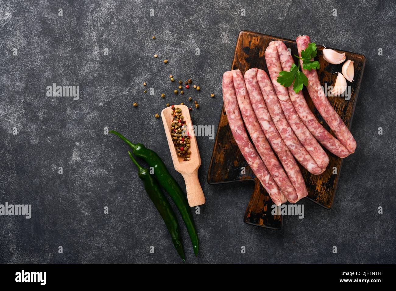 Saucisses crues. Bratwurst ou saucisses avec ingrédients sur planche à découper avec épices sur ...