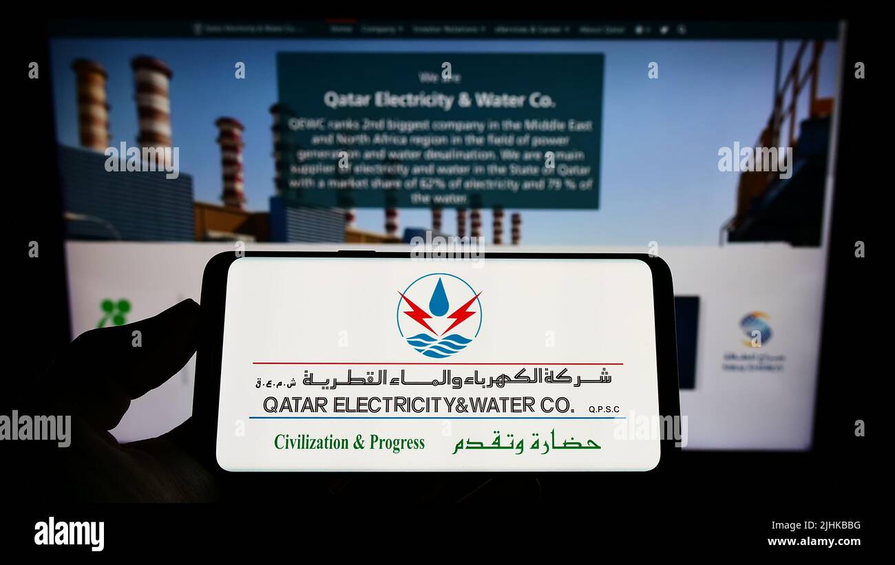 Personne tenant un téléphone portable avec le logo de la société Qatar ...