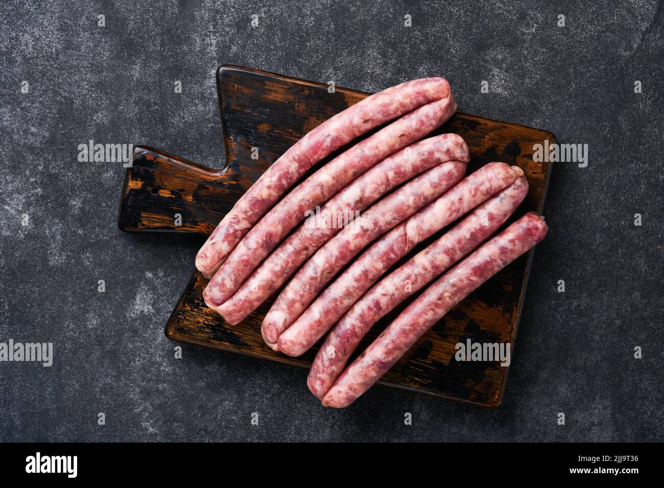 Saucisses crues. Bratwurst ou saucisses avec ingrédients sur planche à découper avec épices sur ...