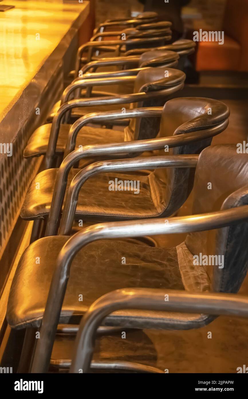 Tabourets de bar en cuir usés alignés sur un bar avec de la lumière qui ...