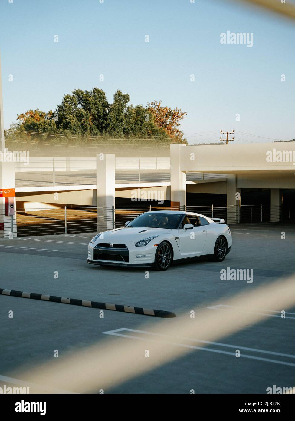 Une photo verticale d'une voiture Nissan GTR blanche dans un parking ...