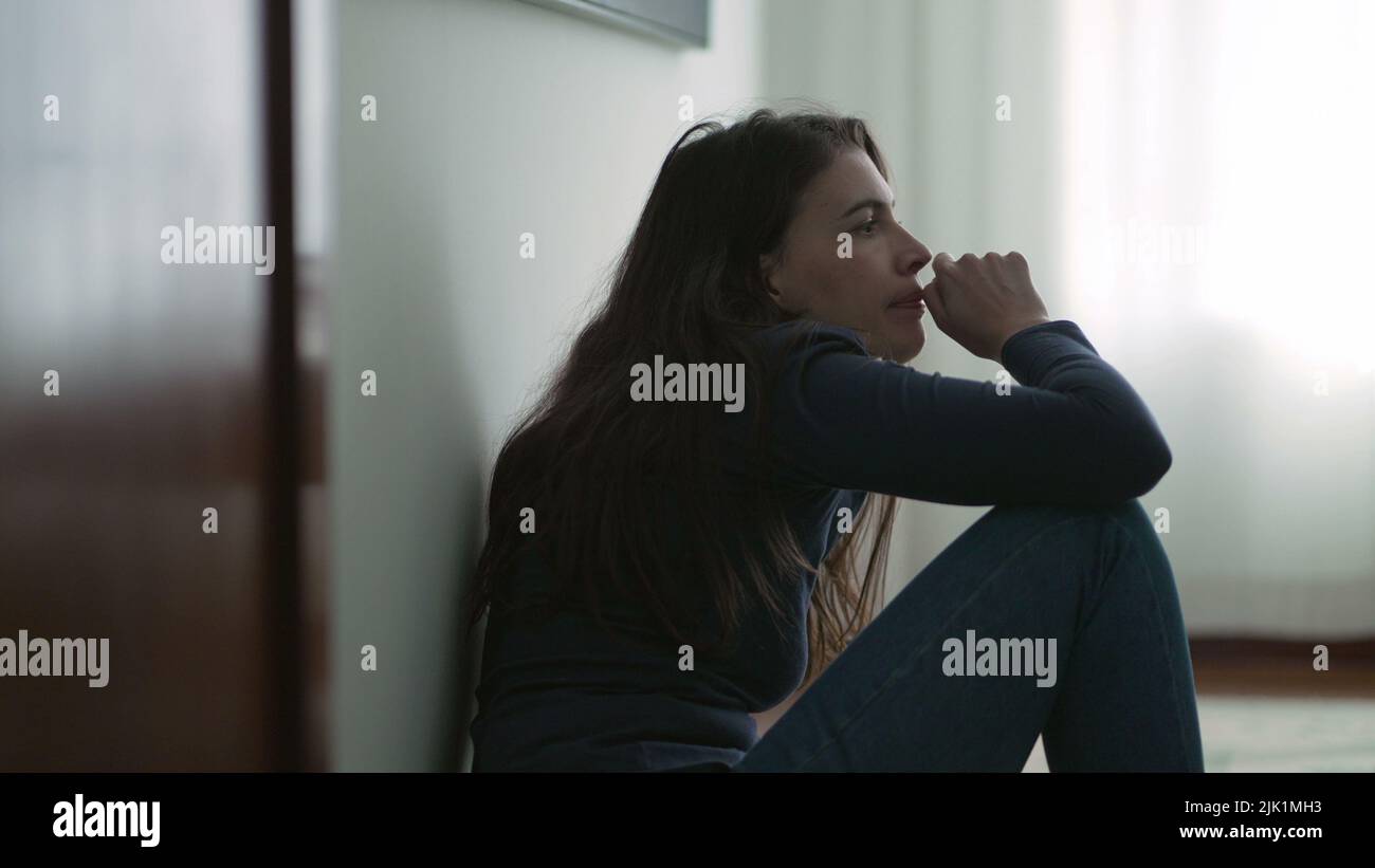 Femme inquiète assise sur le sol souffrant de maladie mentale à la maison. Personne solitaire ...