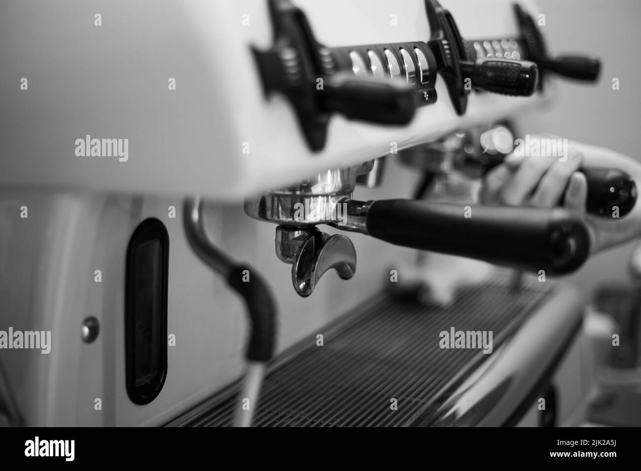 Le barista tient un support et prépare le café avec une machine à café ...