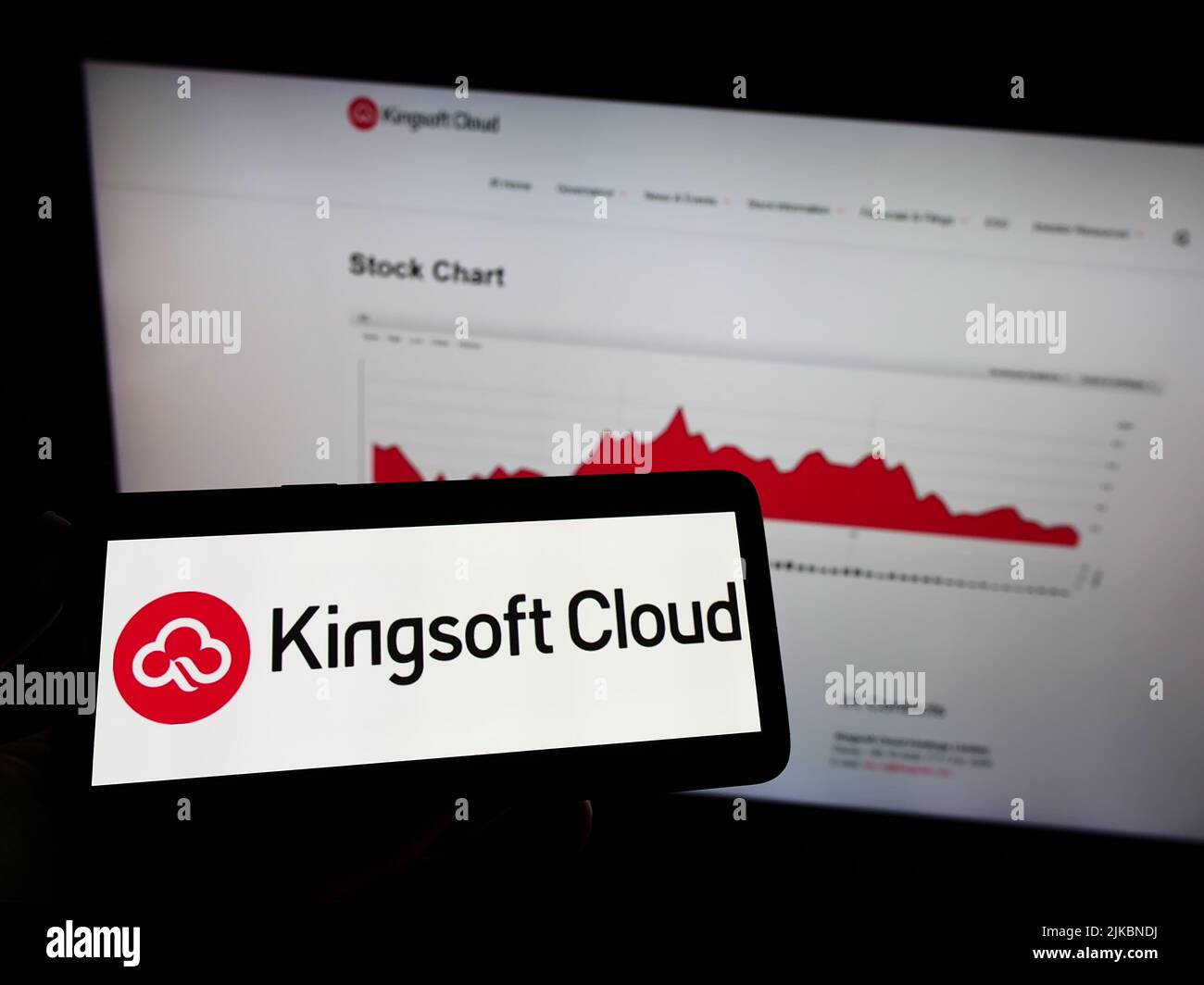 Personne tenant un téléphone portable avec le logo de la société chinoise Kingsoft Cloud ...