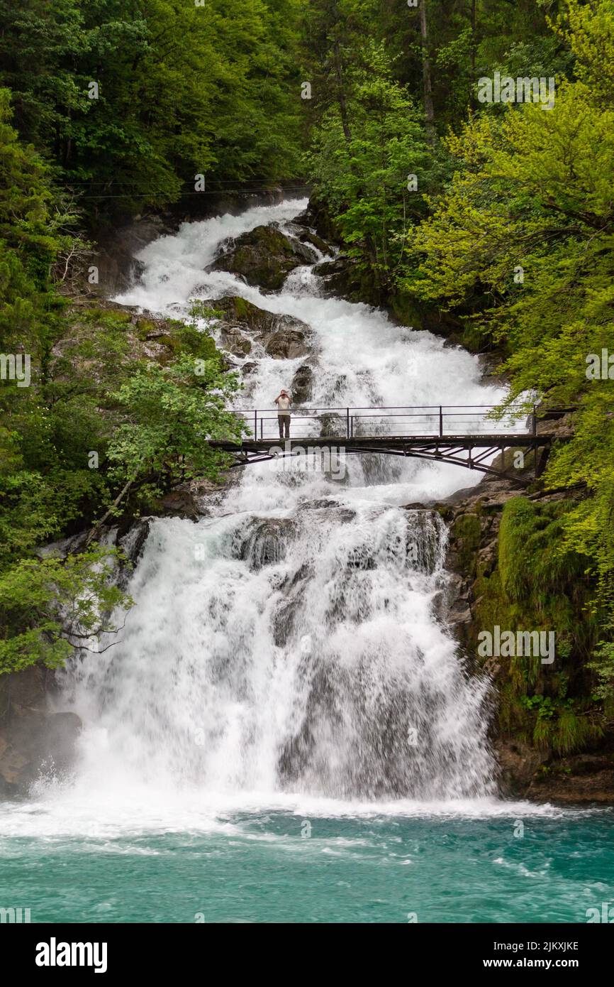 Une photo verticale d'une personne sur un pont au-dessus de cascades ...