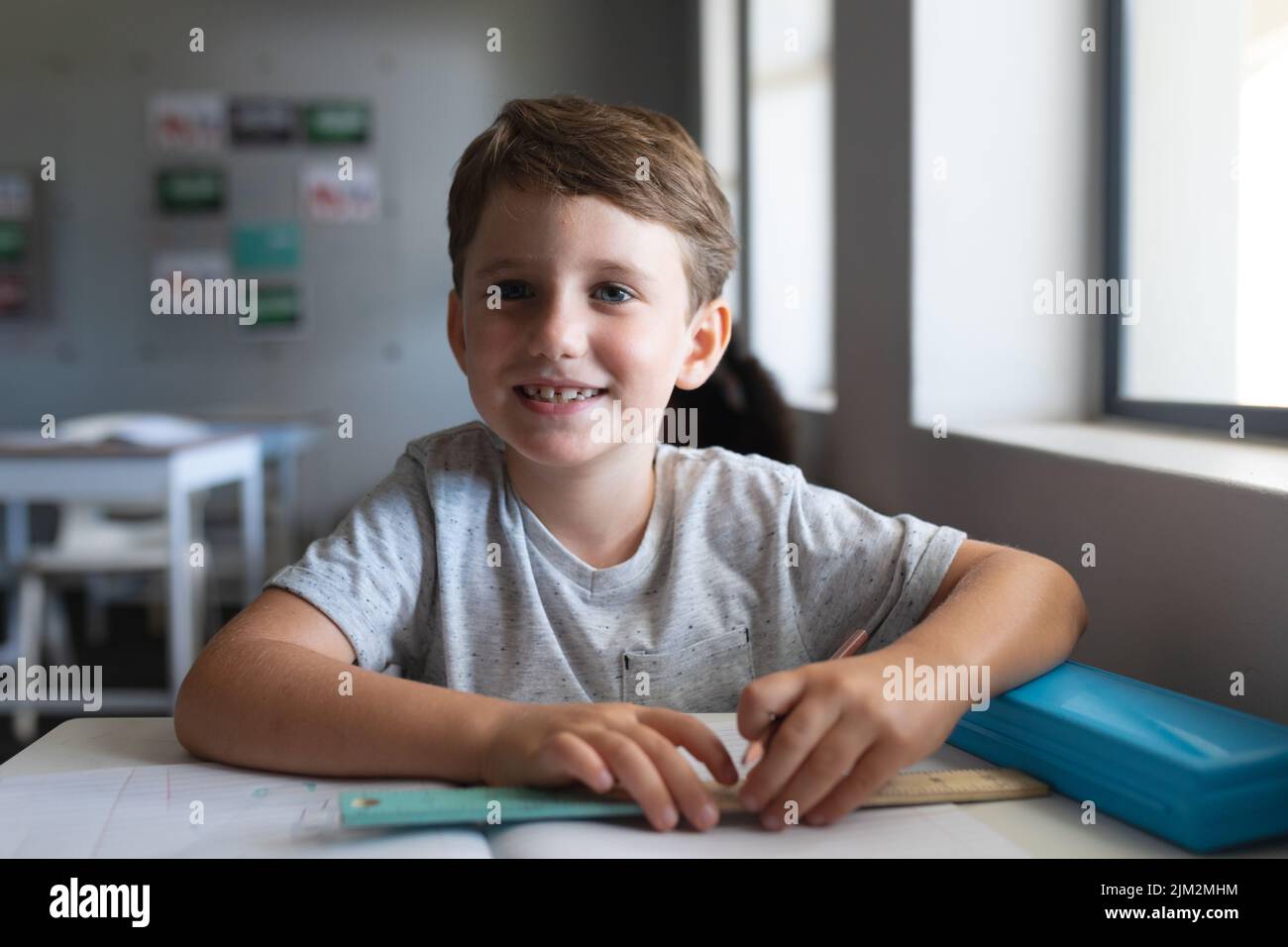Portrait d'un jeune garçon élémentaire caucasien souriant avec un livre ...