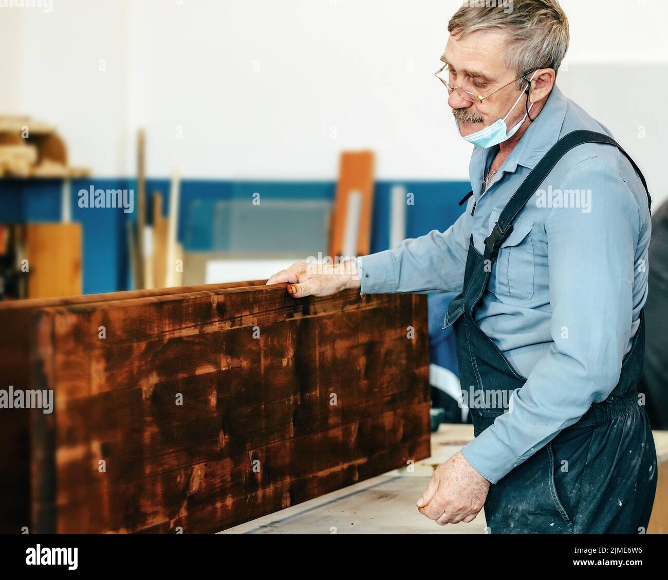 Un charpentier gris-cheveux avec des lunettes travaille avec du bois ...