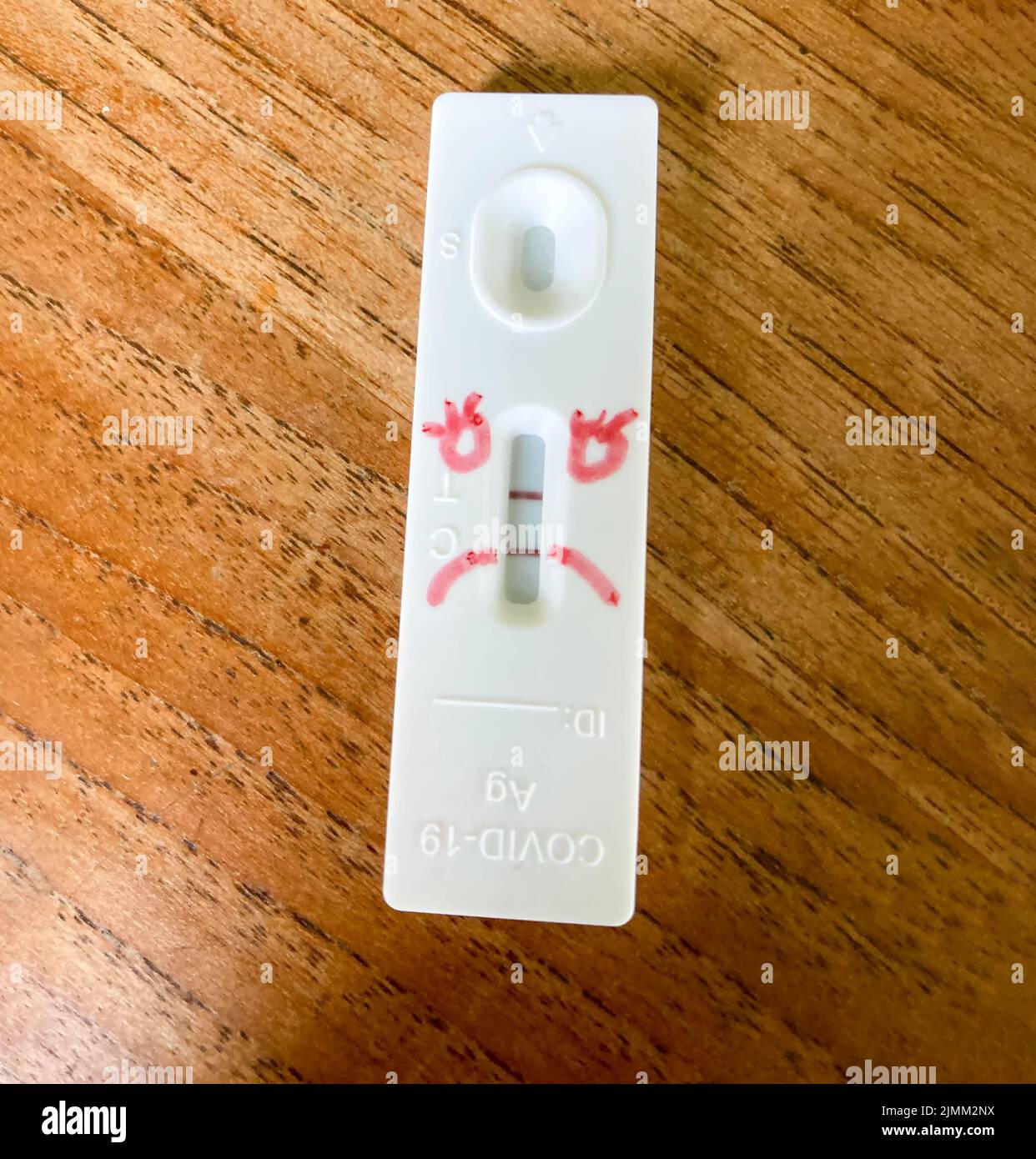 test de corona covid positif sur une table en bois avec un émotiji ...